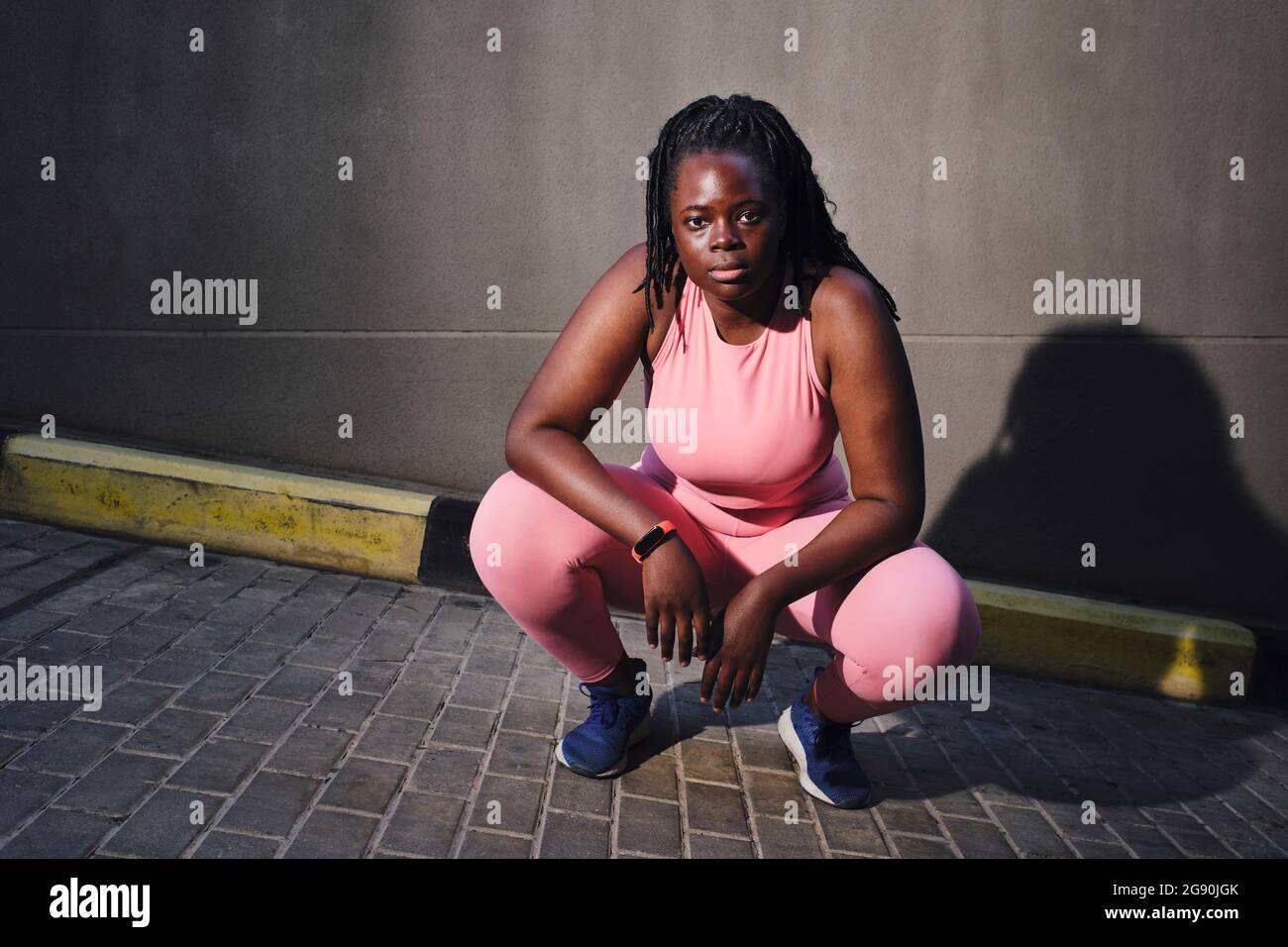 Confident curvy female crouching on footpath Stock Photo - Alamy