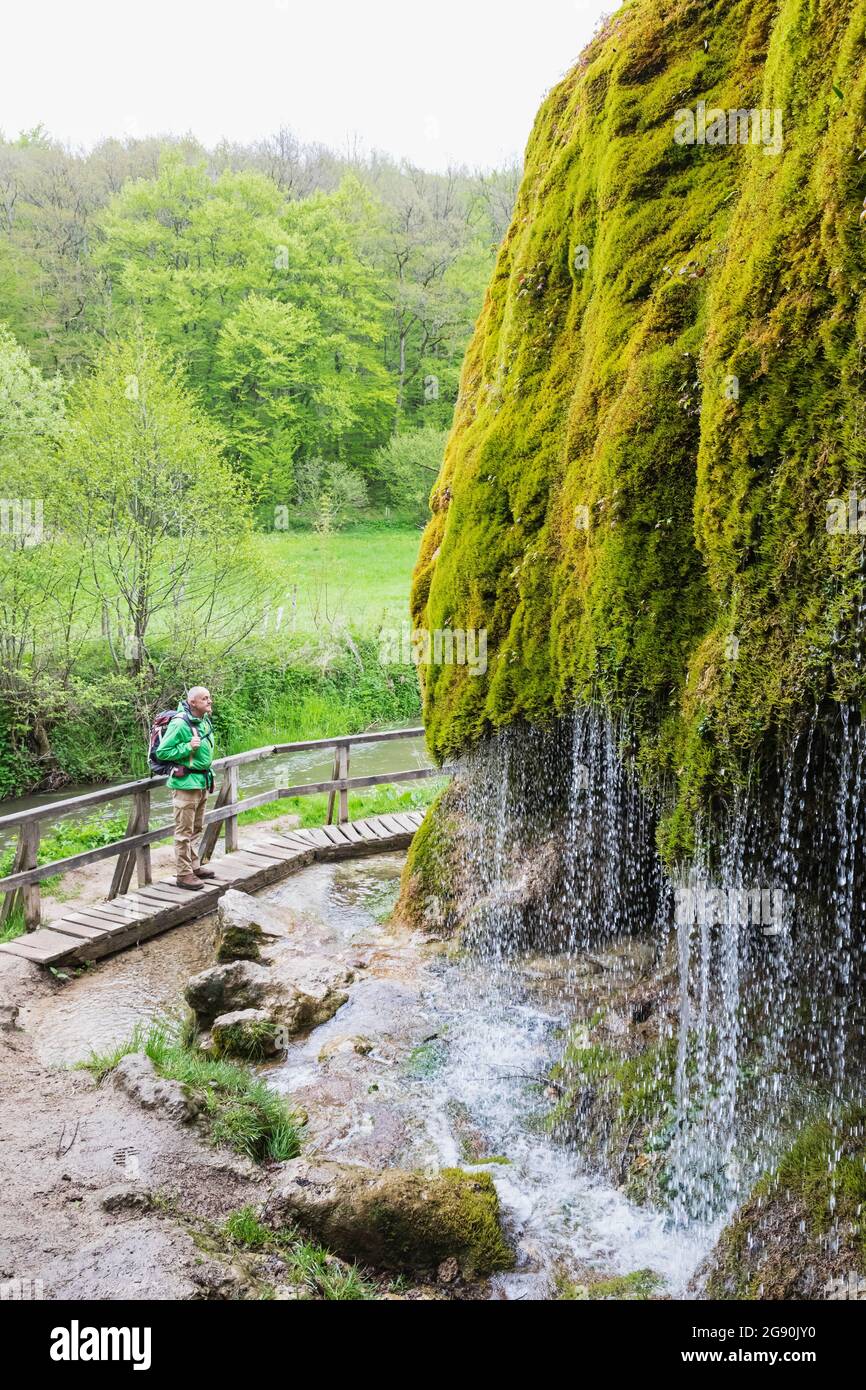 Senior hiker admiring Dreimuhlen waterfall falling down mossy slope ...
