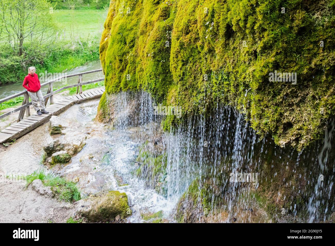 Female hiker admiring Dreimuhlen waterfall falling down mossy slope ...