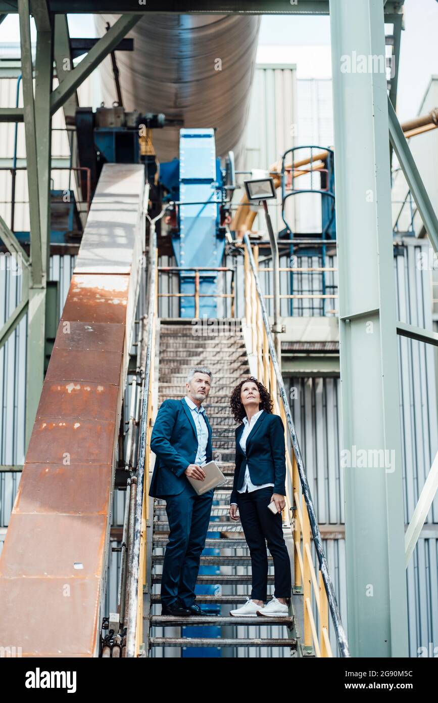Male inspector holding digital tablet while standing with colleague on ...
