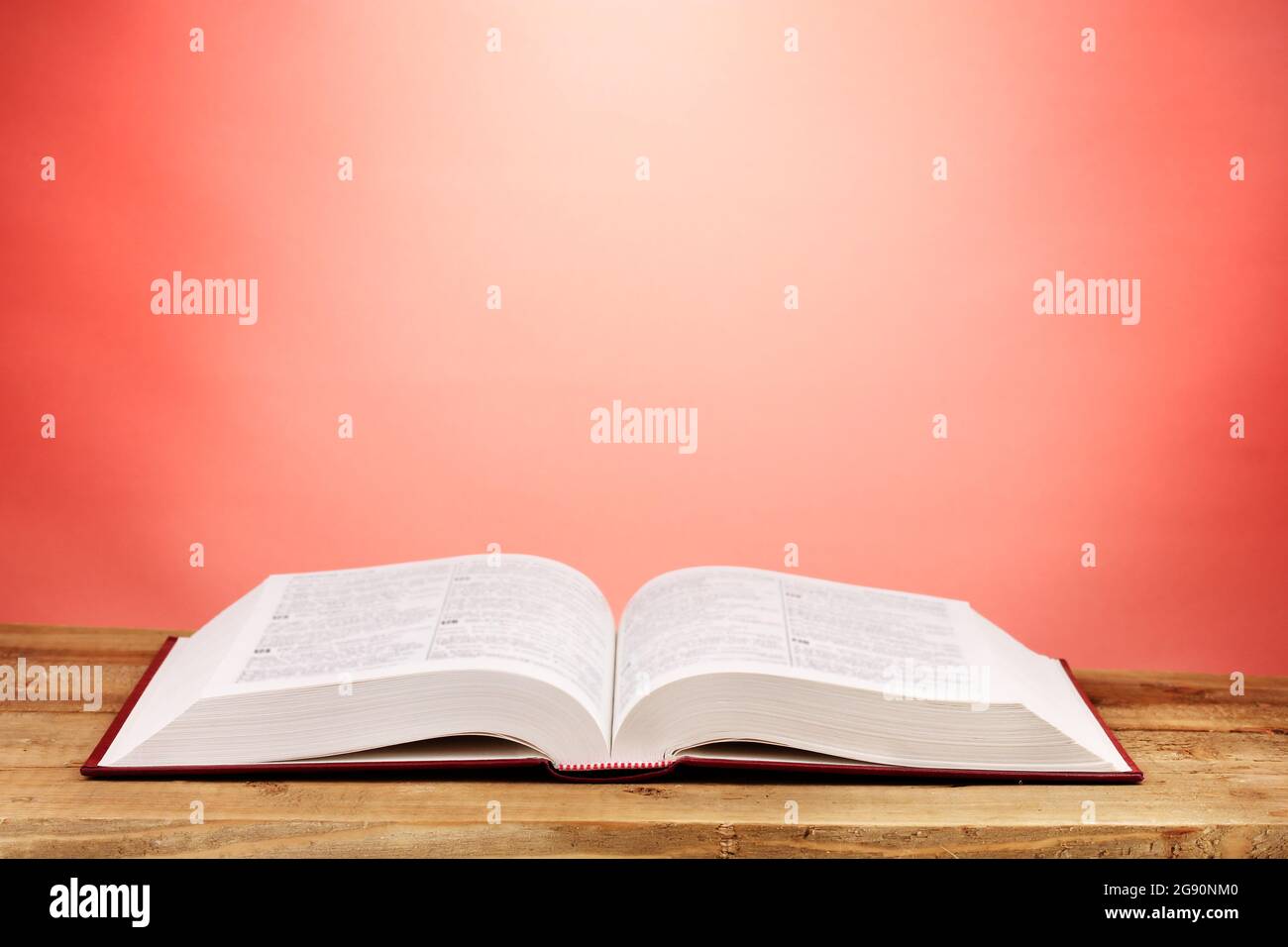 Open book on wooden table on red background Stock Photo - Alamy