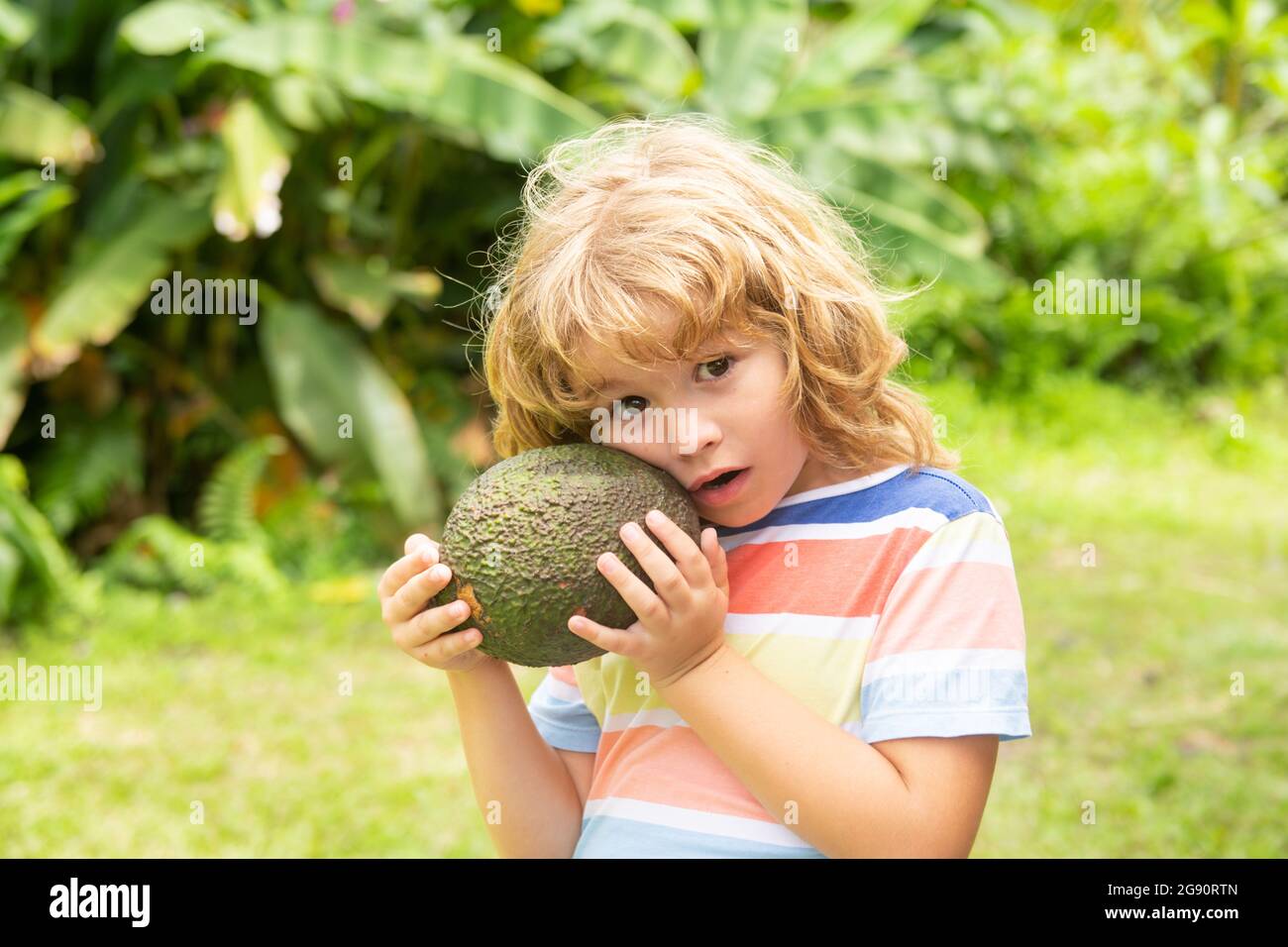 Little sweet child boy holding green avocado. Healthy food for children ...
