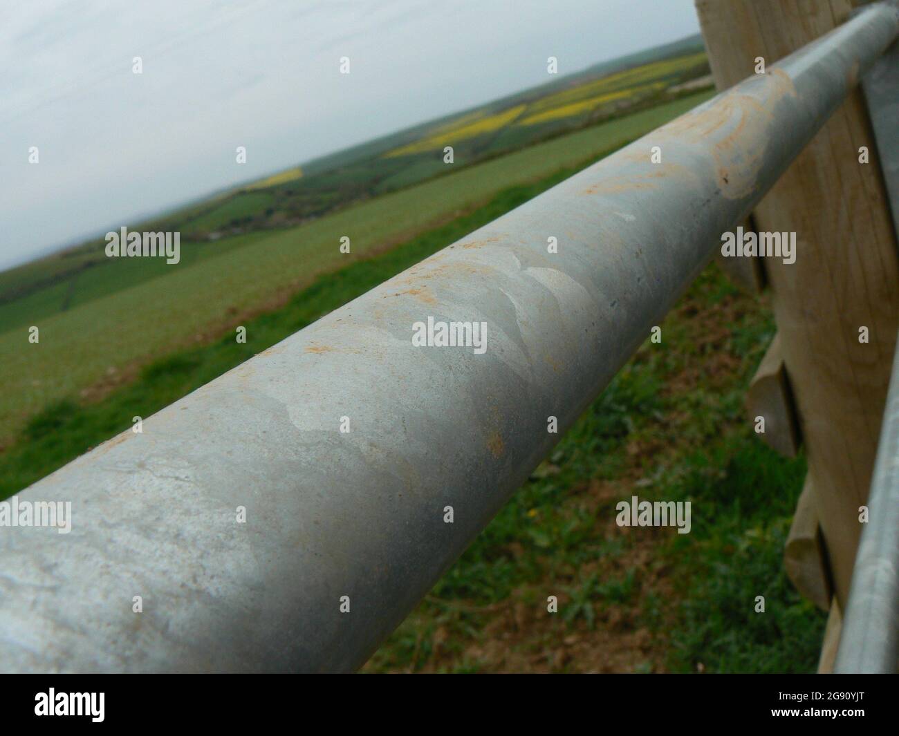 Close up of grey round metal pole (beam or bar) at the top of a gate or ...