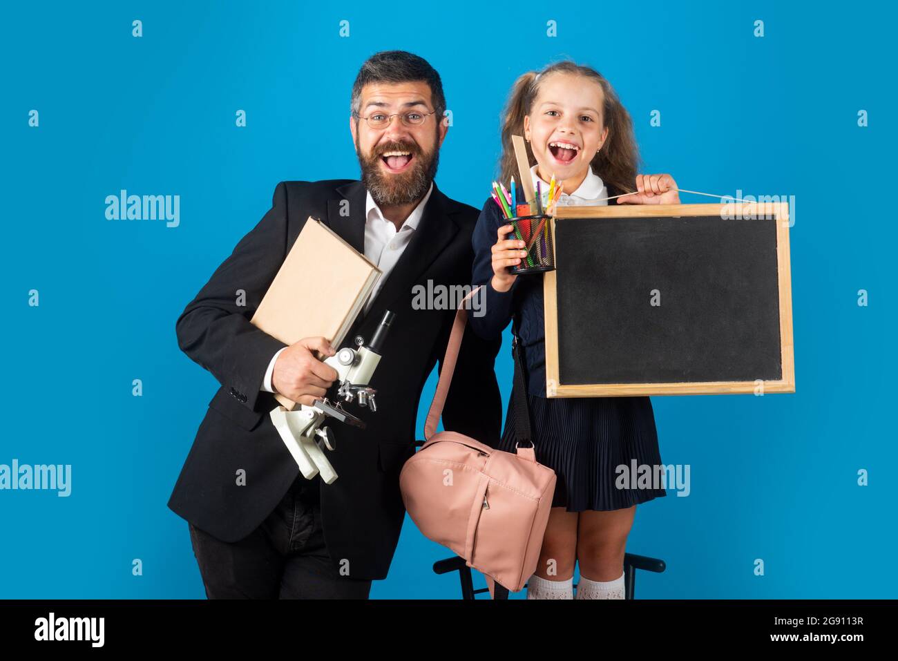 Funny little schoolgirl in school uniform having fun in studio ...