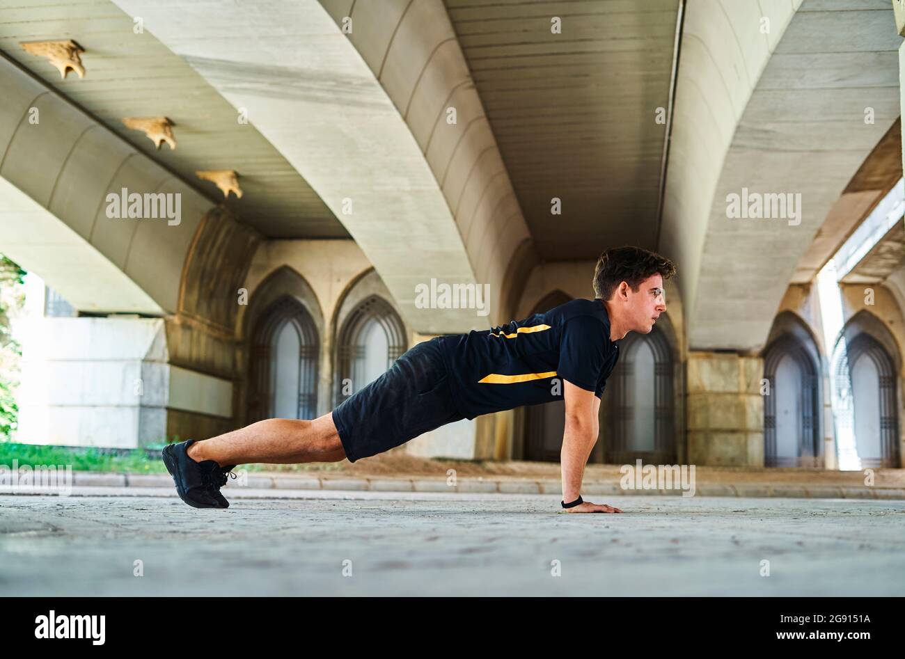 Boy doing stretching before running in the park Stock Photo - Alamy