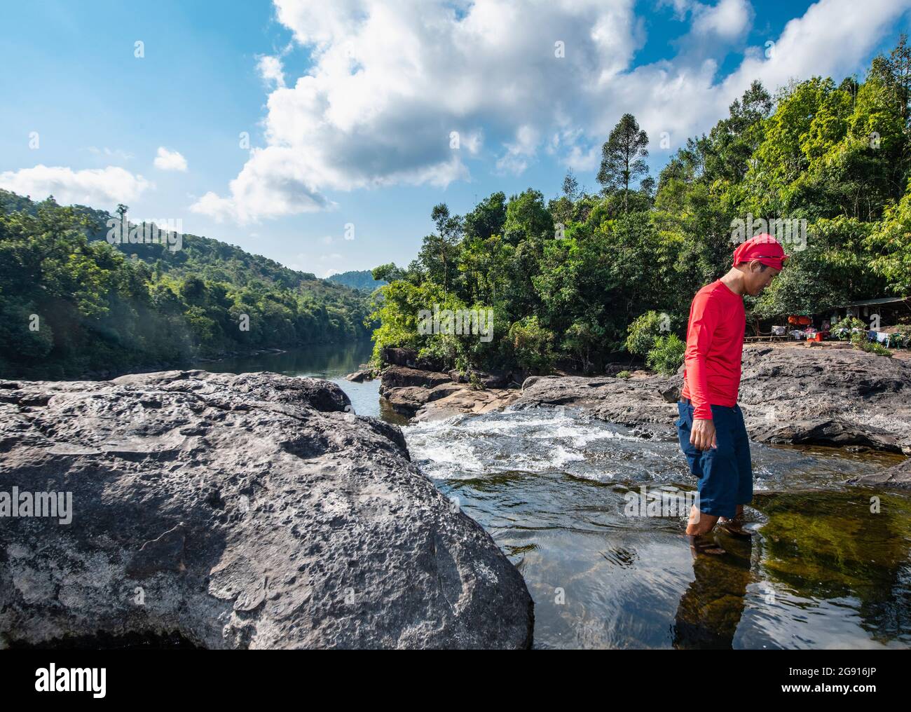Man wading through Tatai river close to Tatai waterfall in Cambodia ...