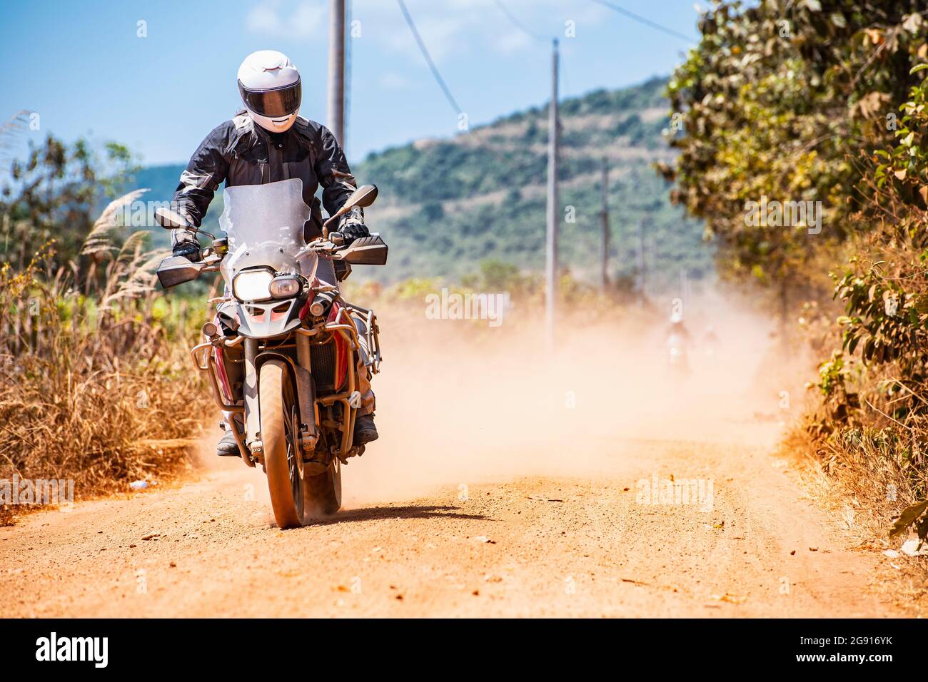 Man riding his adventure motorbike on dusty road in Cambodia Stock ...