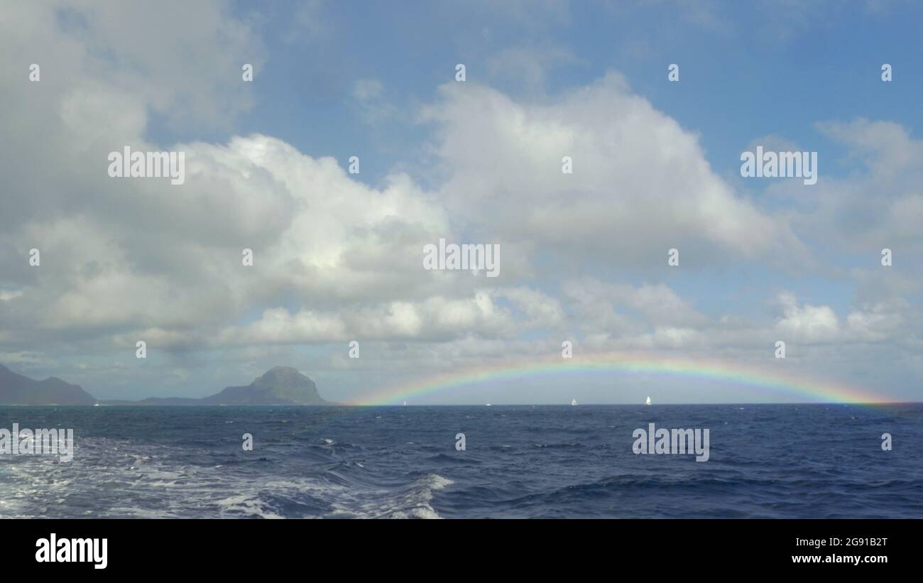 View of rainbow against blue sky with clouds in Indian Ocean, Mauritius ...