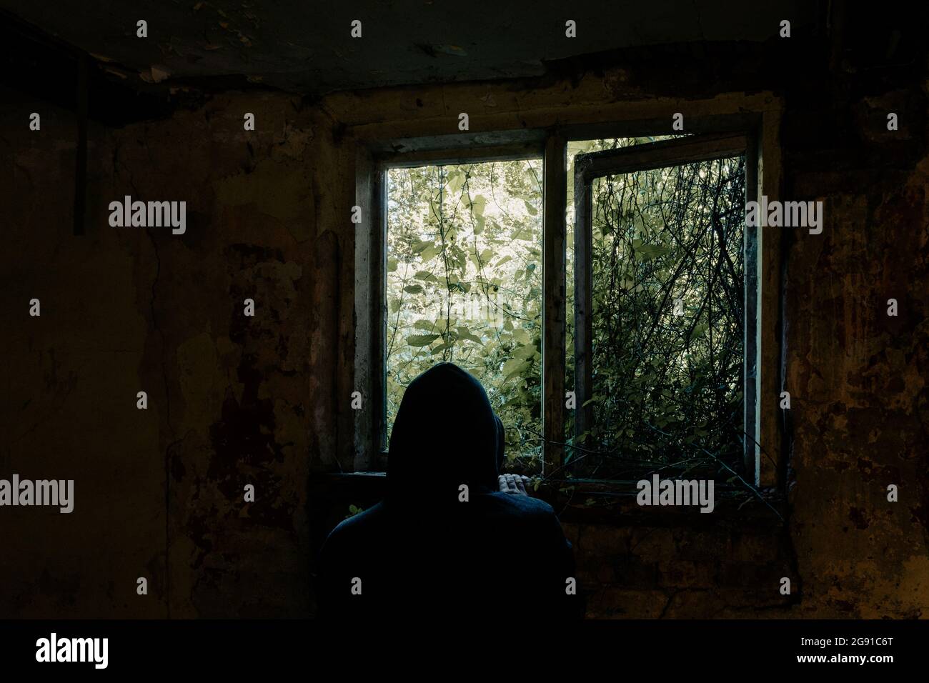 A horror concept. Of a hooded figure, back to camera. Looking out of a ...