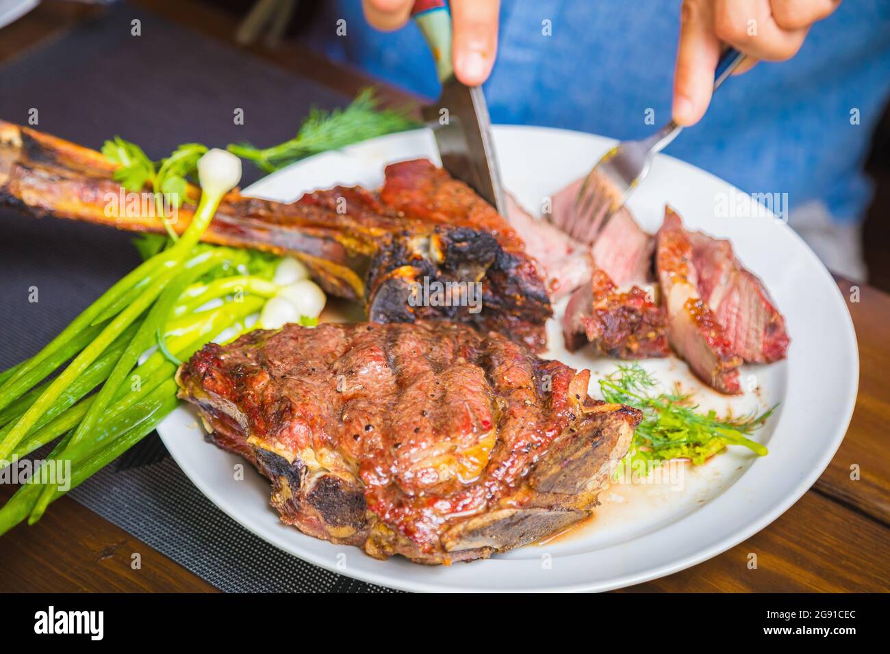 A man cuts cooked fried meat in a plate. Oven-roasted meat for dinner ...