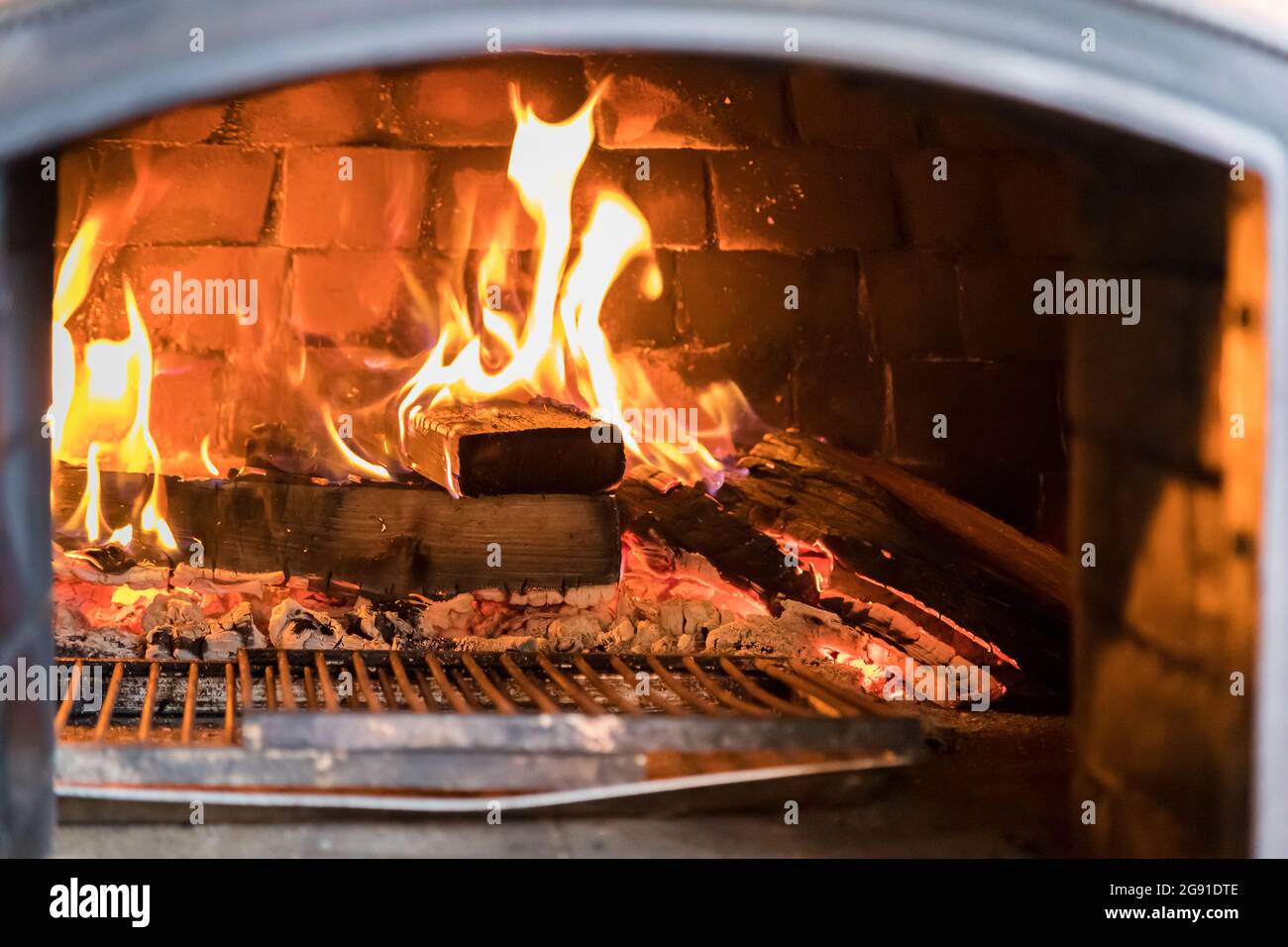 A traditional oven with a burning fire inside for cooking. Firewood and ...
