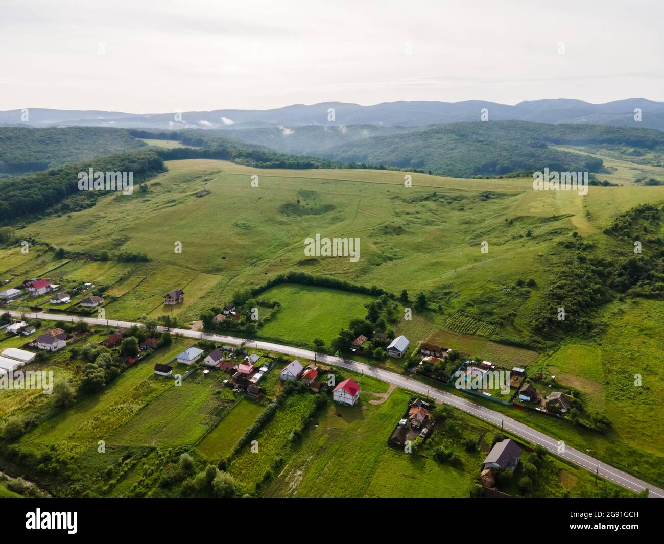 Aerial view of rural Romania, with houses, green forests and fields ...