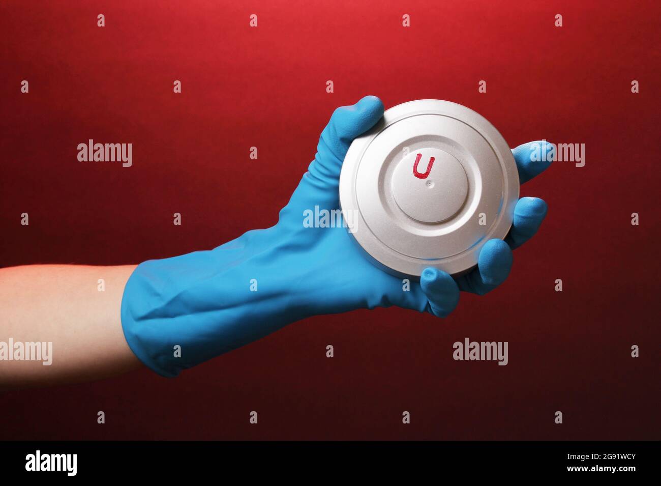 Uranium in hand on red background Stock Photo - Alamy
