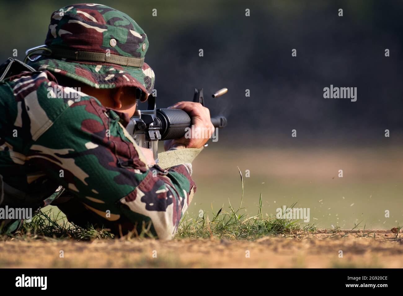 Soldier firing rifle gun to target with bullet cartridge in the air ...