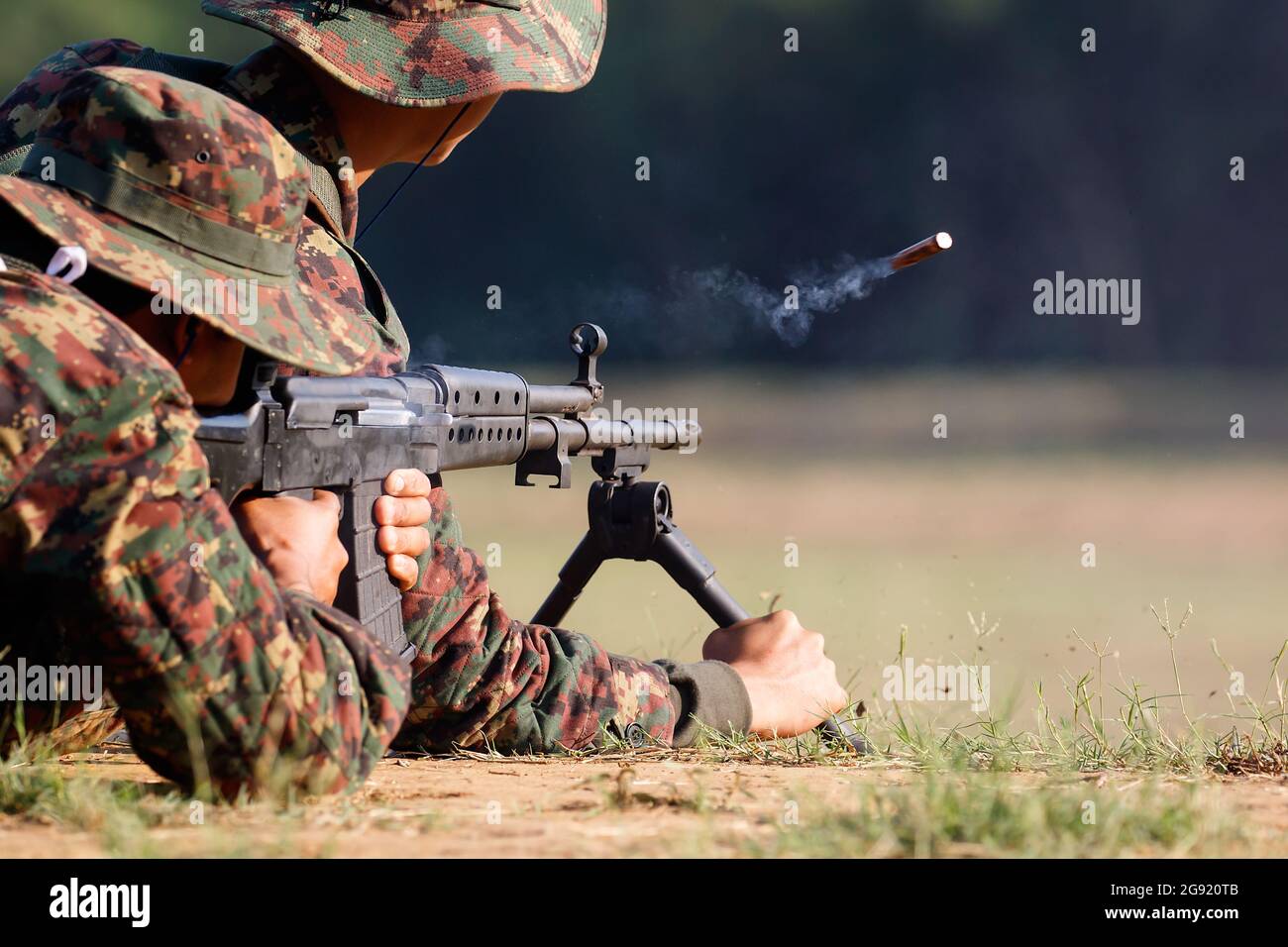 Soldier firing rifle gun to target with bullet cartridge in the air ...