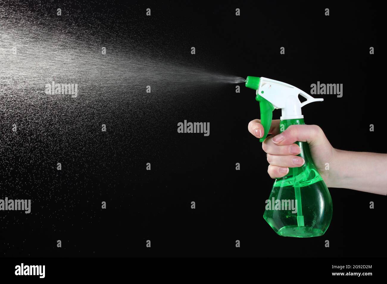 hand holding spray bottle and spraying on black background Stock Photo ...