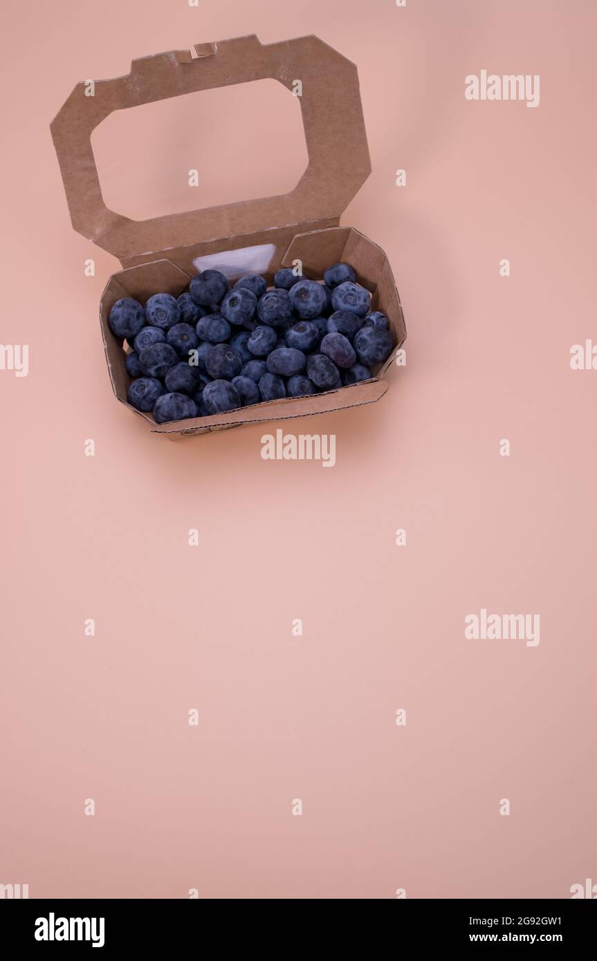 Box of blueberries isolated on a pink background with free space for ...