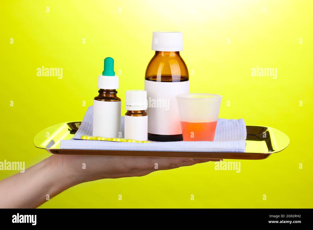 Hand holding tray with medicines on green background Stock Photo - Alamy