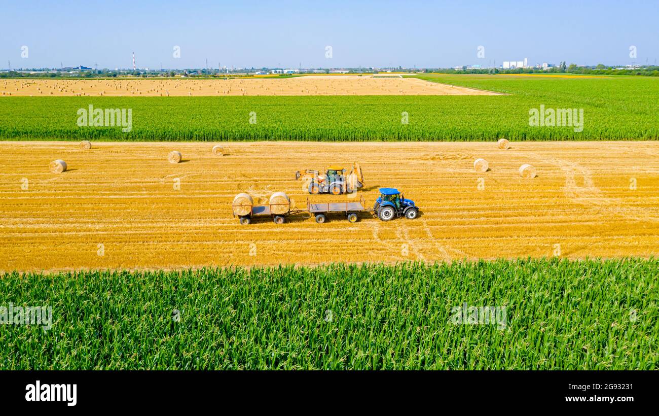 Above view on excavator as loading straw bales on trailer, tow by ...