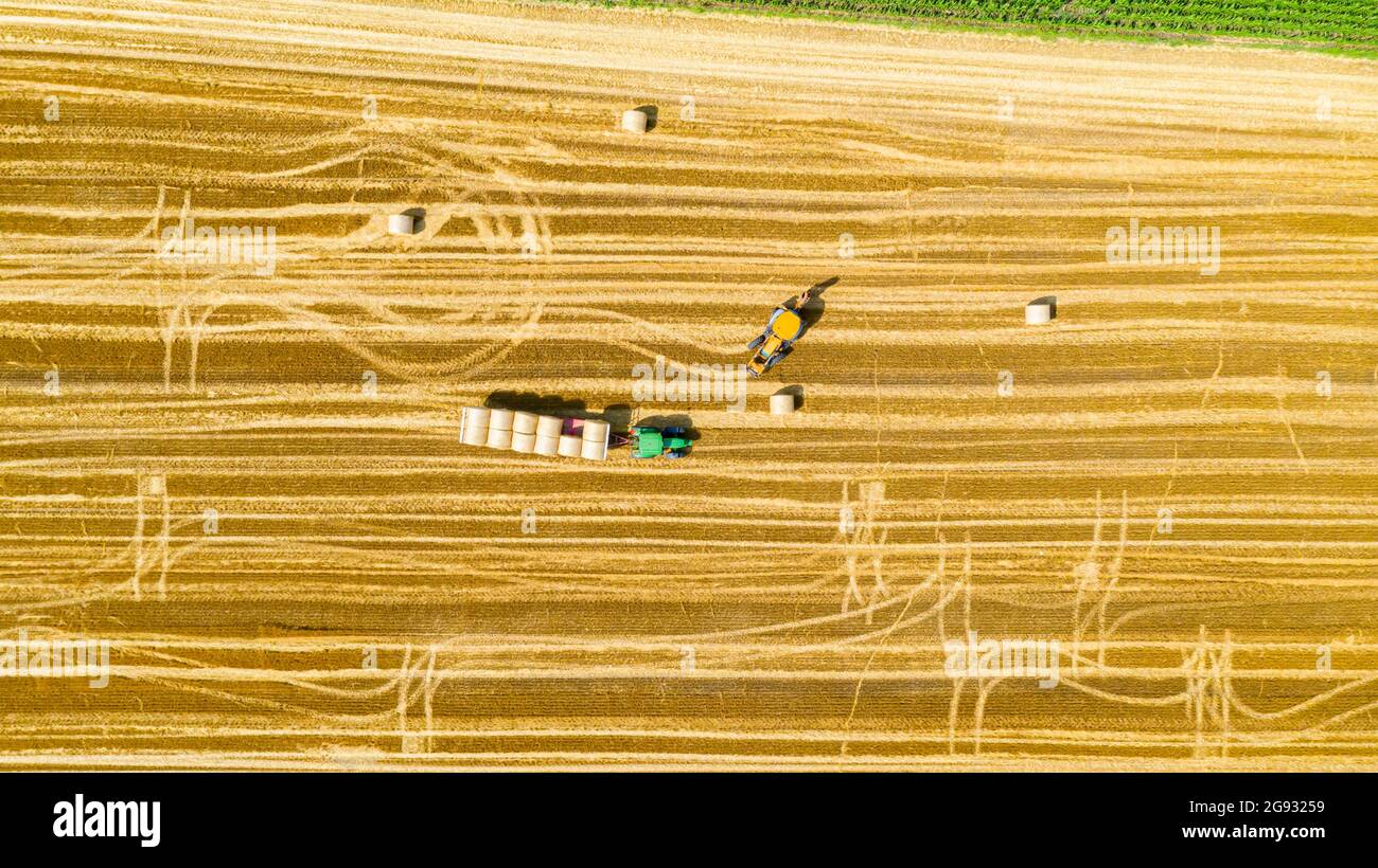 Above top view on excavator as loading straw bales on trailer, tow by ...
