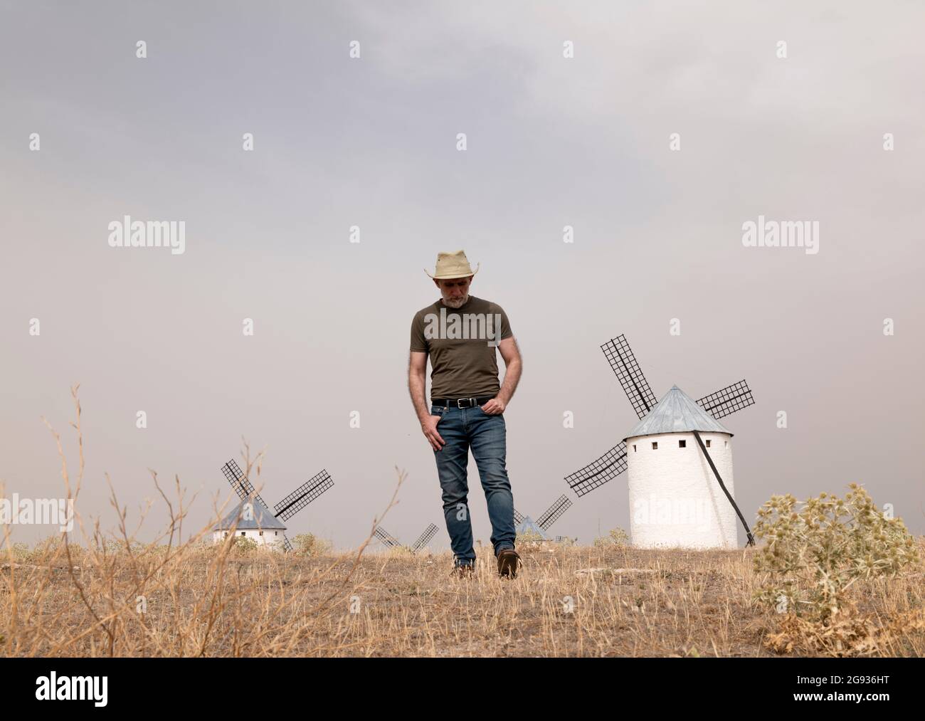 A man wearing a cowboy hat with windmills in the countryside Stock ...