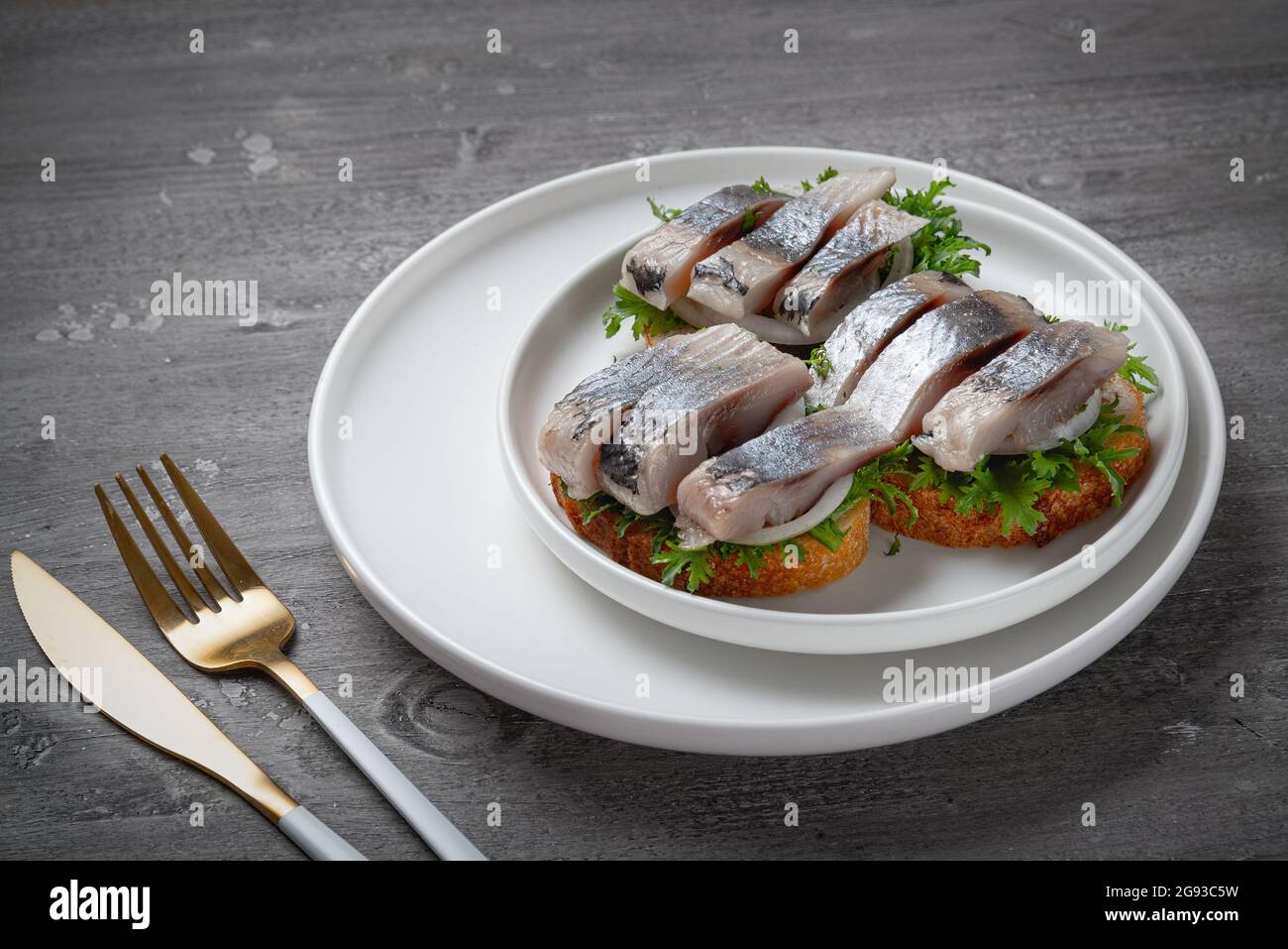 Delicious salted herring with onions in a white plate. Rustic style ...