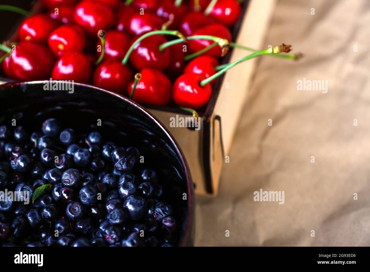 Cropped bowl of blueberries and box, crape of red sweet cherries with ...