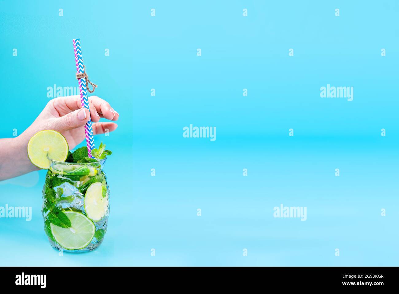 Female hand holding a glass with mojito cocktail with straws. Copy ...