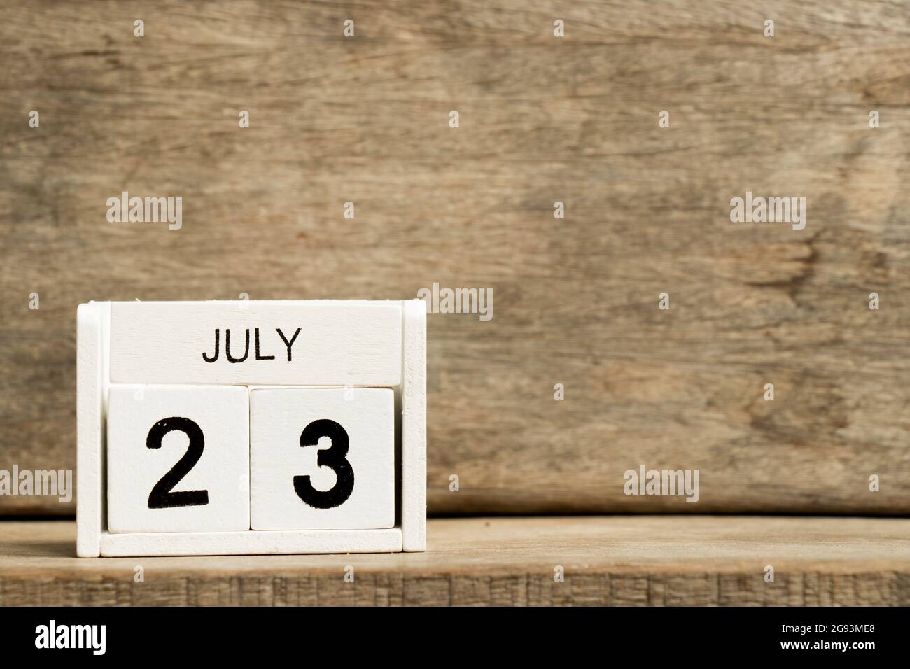 White block calendar present date 23 and month July on wood background ...