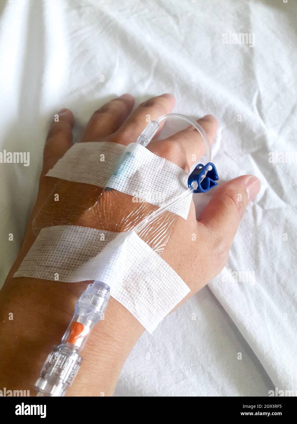 Patient hand with the tube of normal saline infusion on white cloth ...