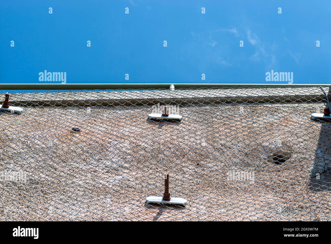 A stone wall standing by a road secured with a galvanized metal mesh ...