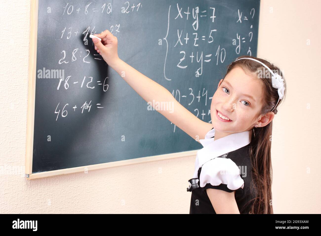 beautiful little girl writing on classroom board Stock Photo - Alamy