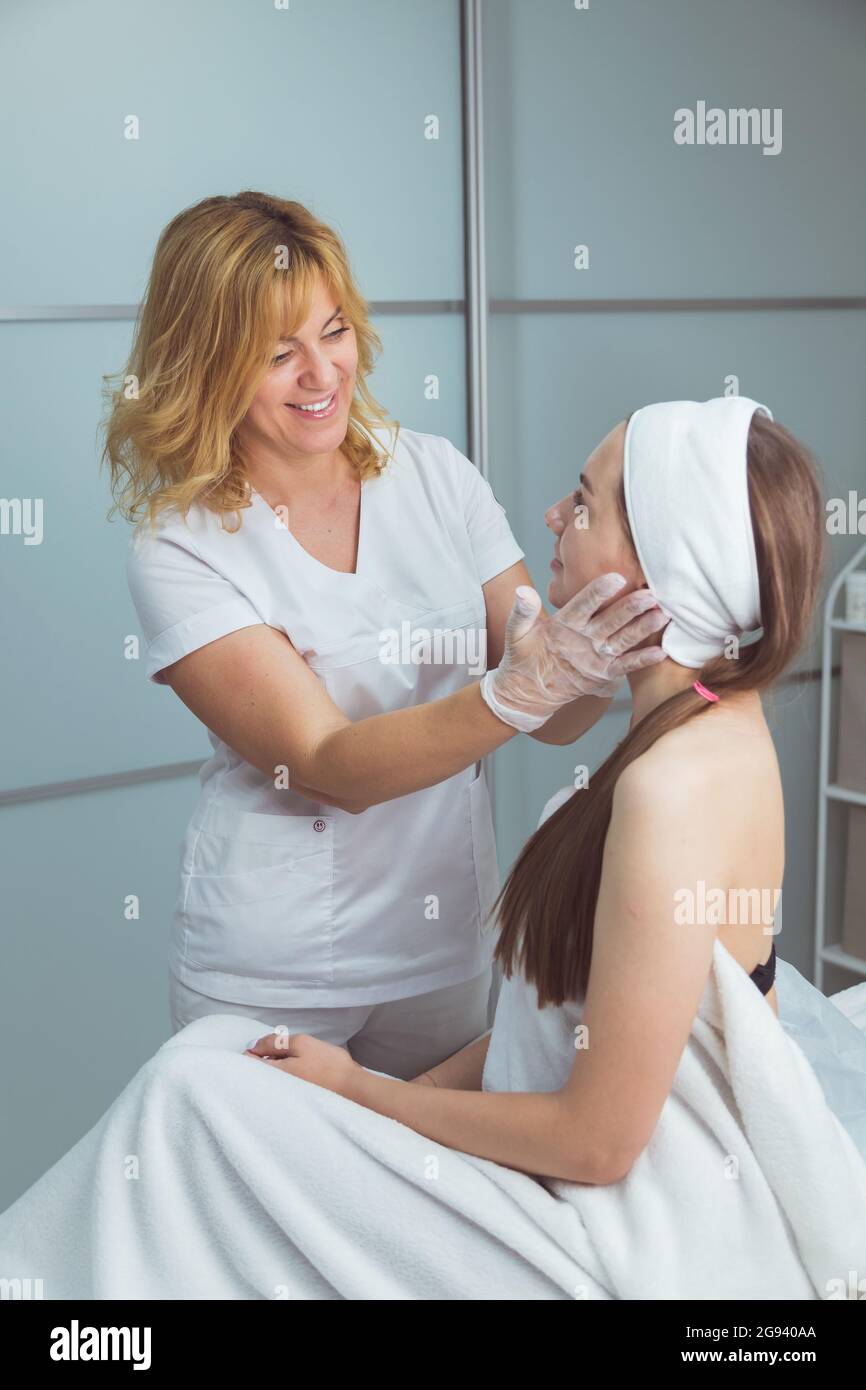 Doctor examining young woman face before cosmetic procedures Stock ...