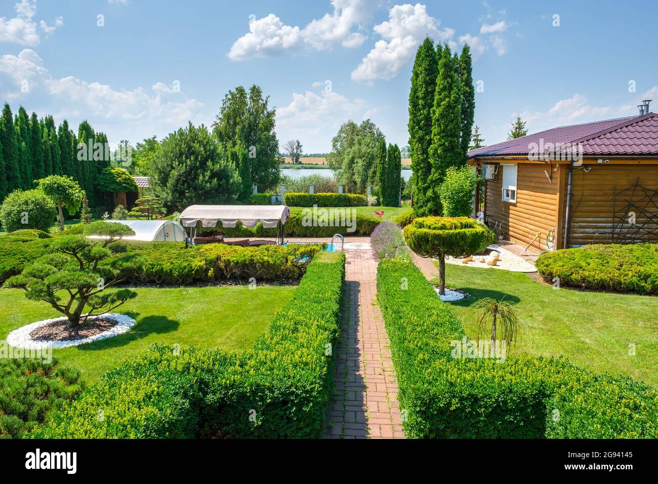 Beautiful backyard garden with nicely trimmed trees, bushes and stones ...