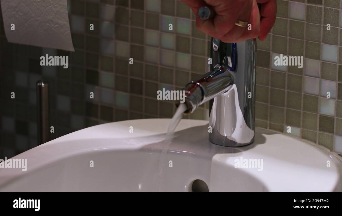 Man hand opening tap with water in bidet. Contemporary ceramic ...