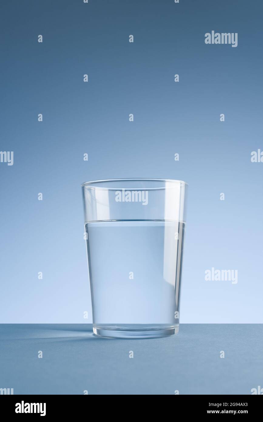 Minimalist photo of a glass of clean drinking water on blue background ...