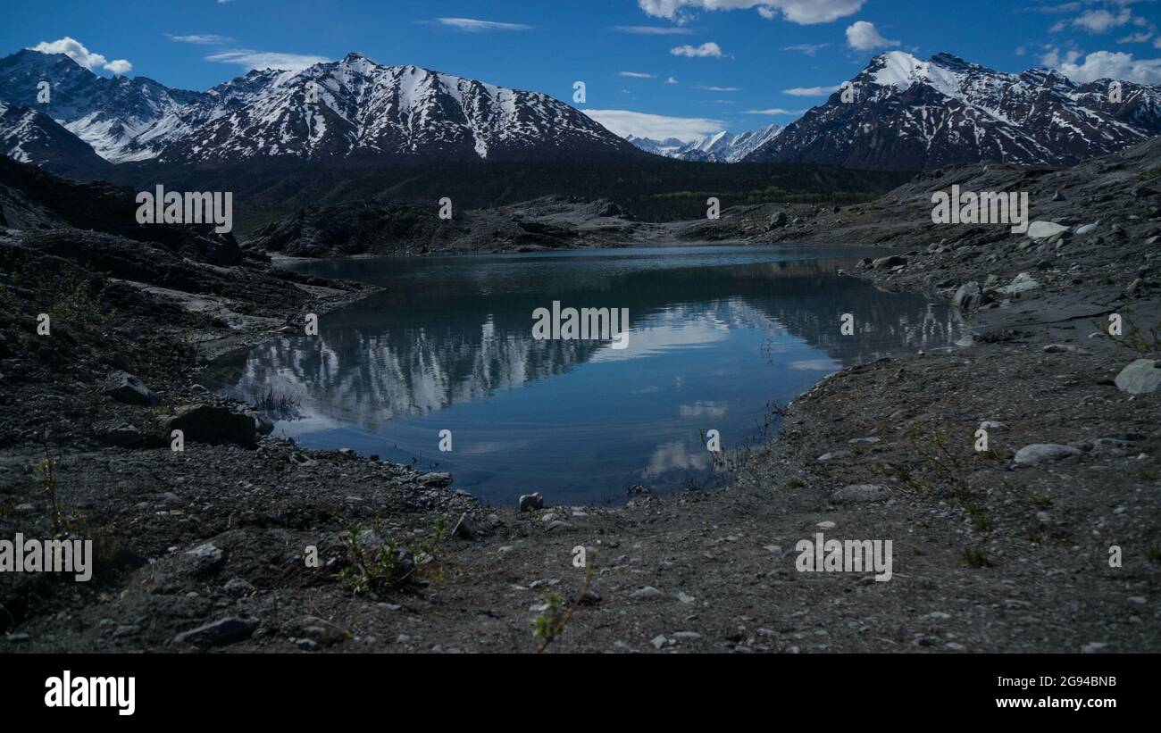 Small reflecting lake near the snowy mountains Stock Photo - Alamy