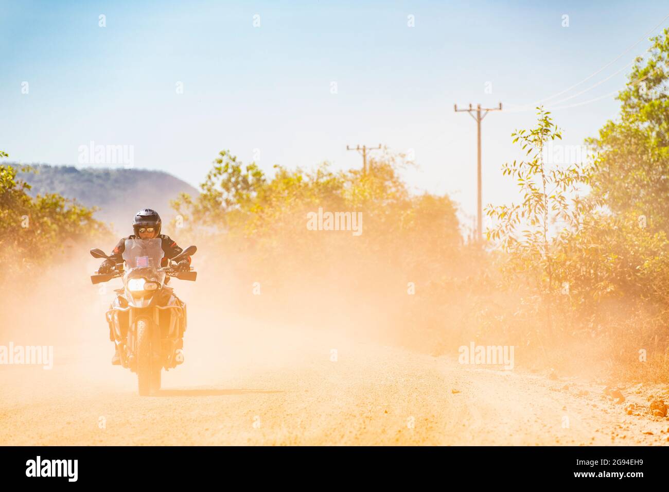 Man riding his adventure motorbike on dusty road in Cambodia Stock ...