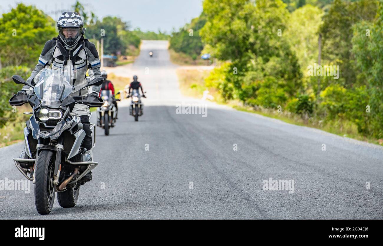 Men riding their adventure motorbikes on straight road in Cambodia ...