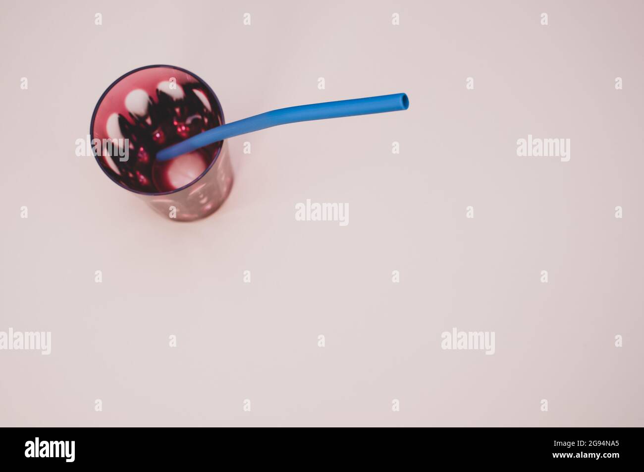 Closeup shot of a reusable bend straw in a glass isolated on pink ...