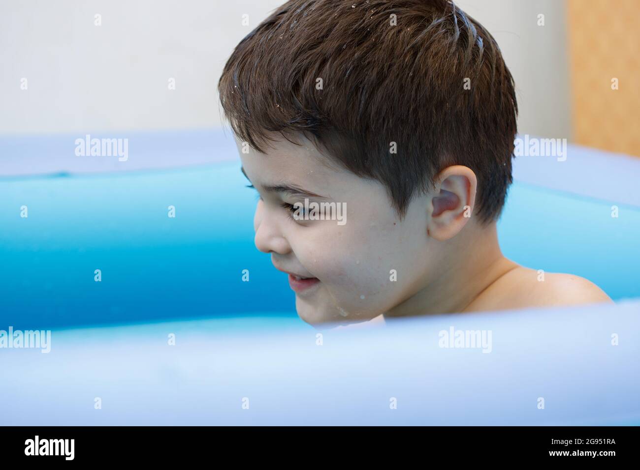 portrait. a six-year-old boy in a children's inflatable pool. selective ...
