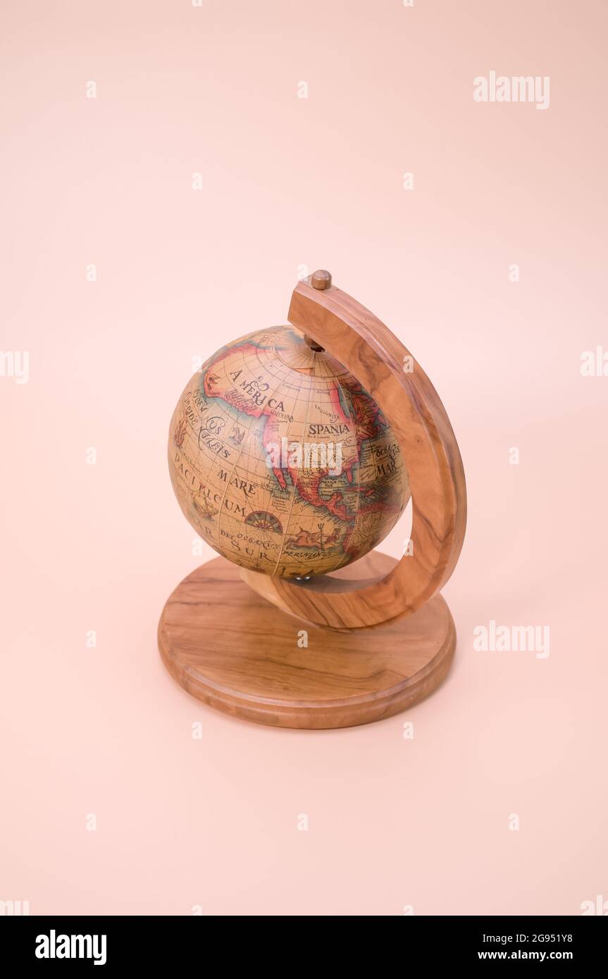 Vertical shot of a small wooden globe isolated on a pink background ...