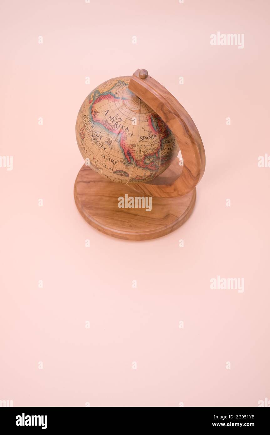 Vertical shot of a small wooden globe isolated on a pink background ...