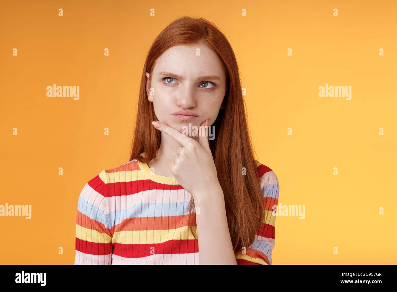 Perplexed hesitant serious-looking ginger girl blue eyes weihing ...