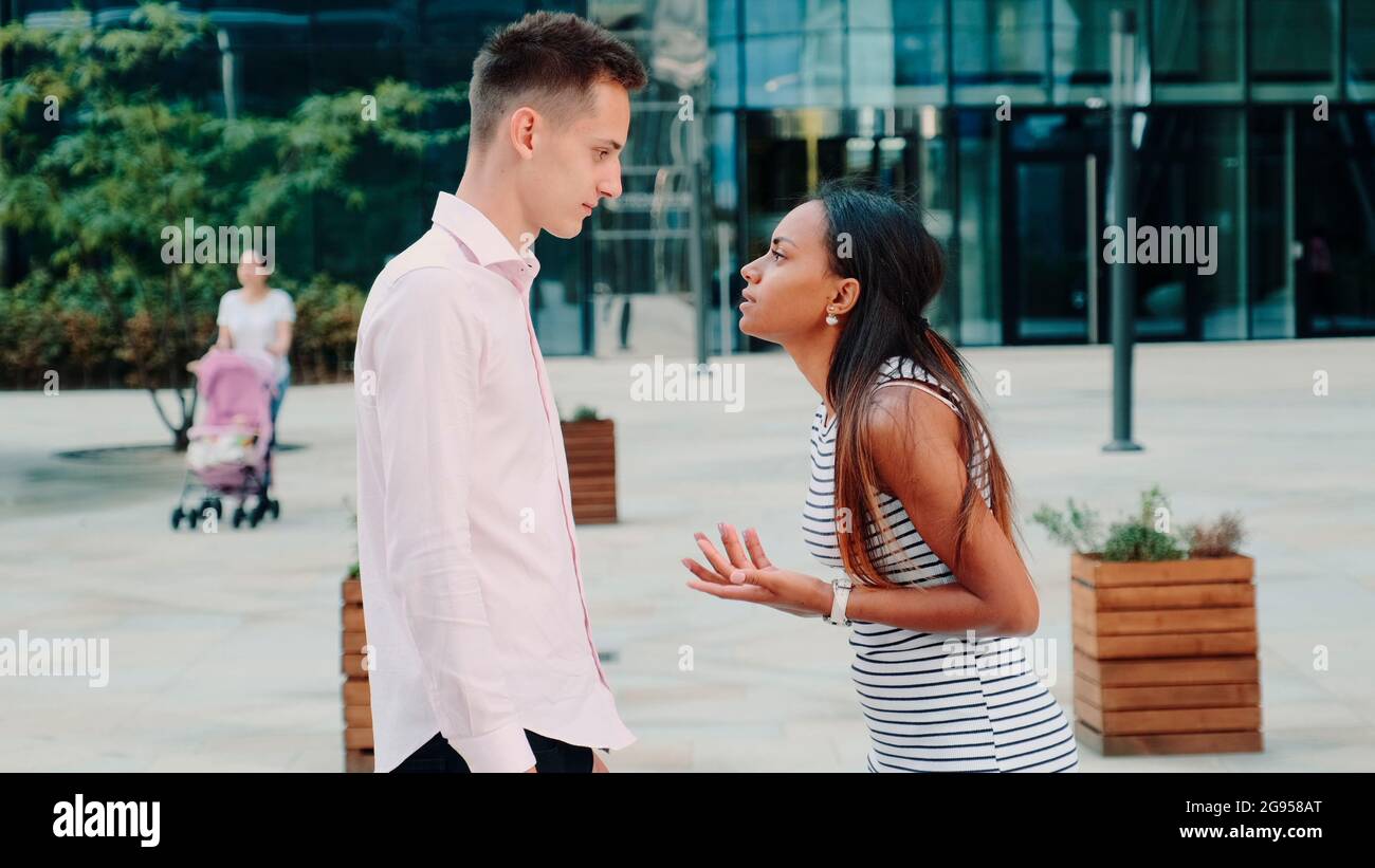 Young black woman quarreling with her husband on the street and pushing ...