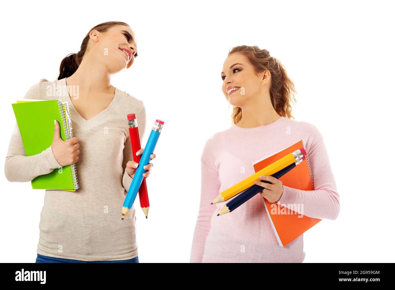 Portrait of a cute young student girls holding colorful notebooks ...