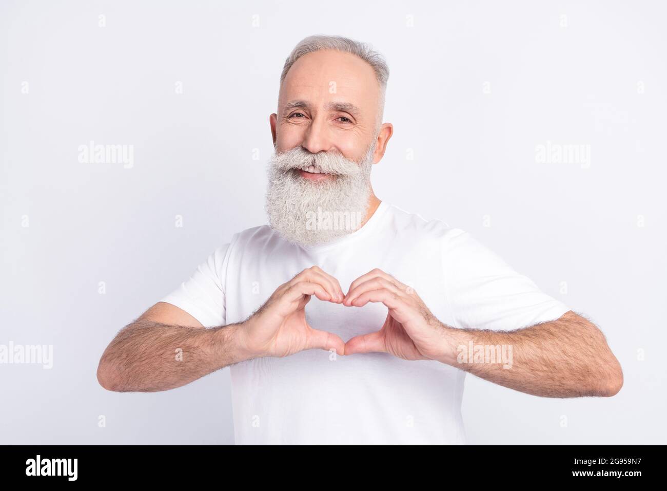 Portrait of attractive cheerful man boyfriend showing heart shape sign ...