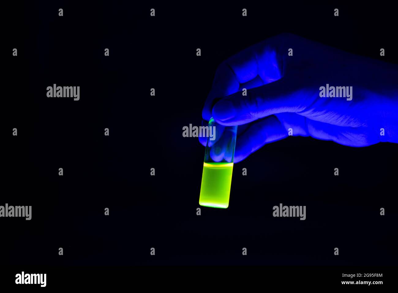 A scientist holding chemistry photochemical reaction green glass vials ...