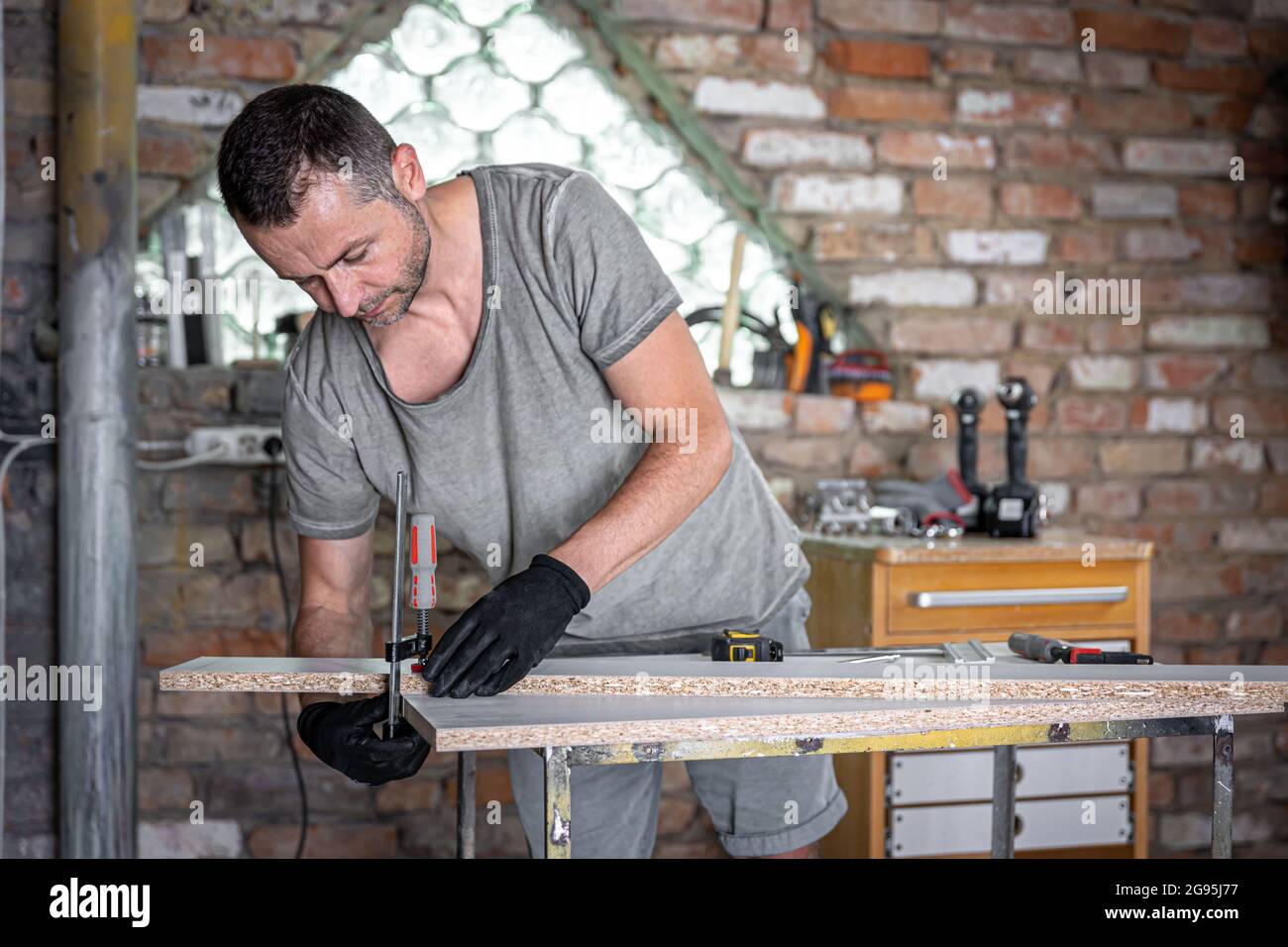 Carpenter doing wood work using clamping hand tool in his workshop ...