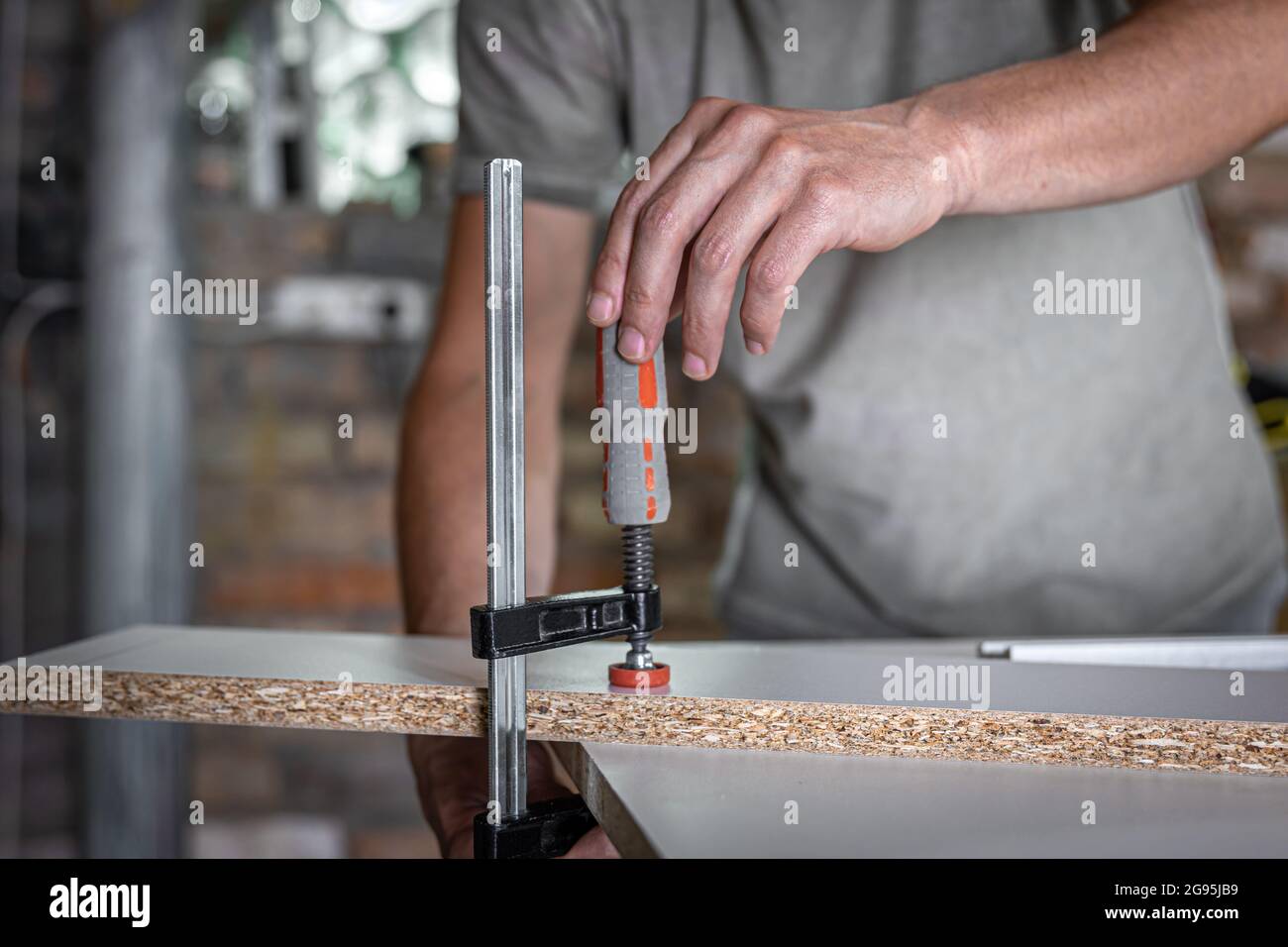Carpenter doing wood work using clamping hand tool in his workshop ...